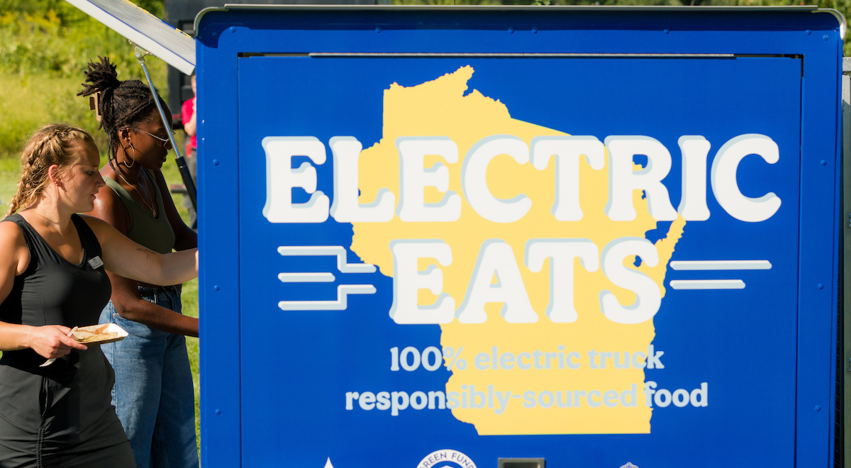 Two students getting food from the open Electric Eats food truck